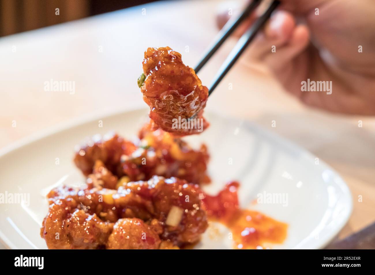 Chopsticks holding Korean fried chicken Stock Photo - Alamy