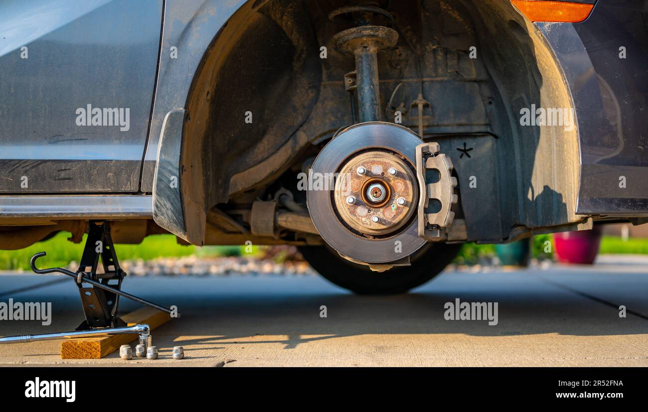 Wheel well of a vehicle lifted with a tire jack. Rusted hub and strut ...