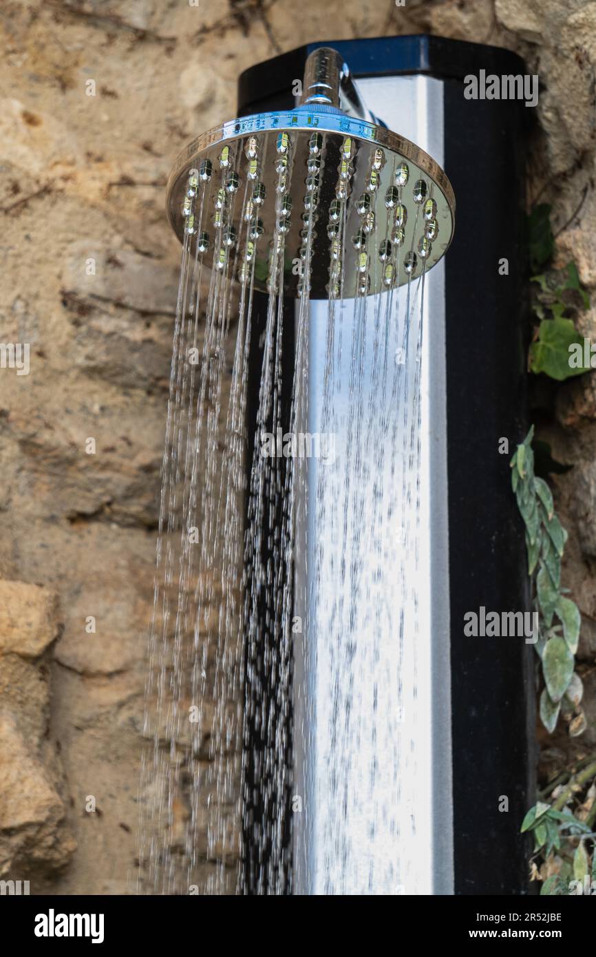 Shower in the street over a stone wall spraying water Stock Photo - Alamy