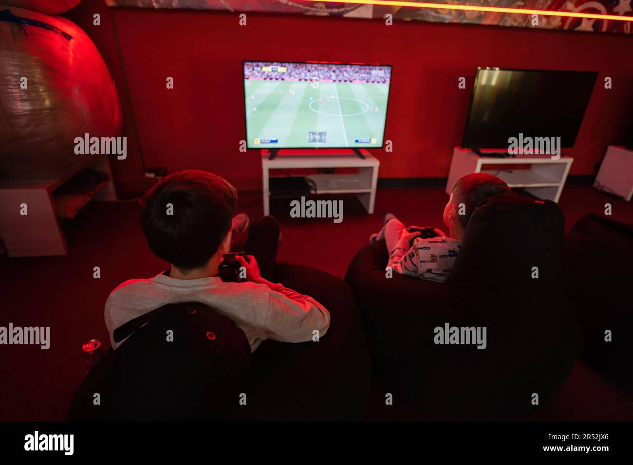 Two boys gamers play football gamepad video game console in red gaming ...