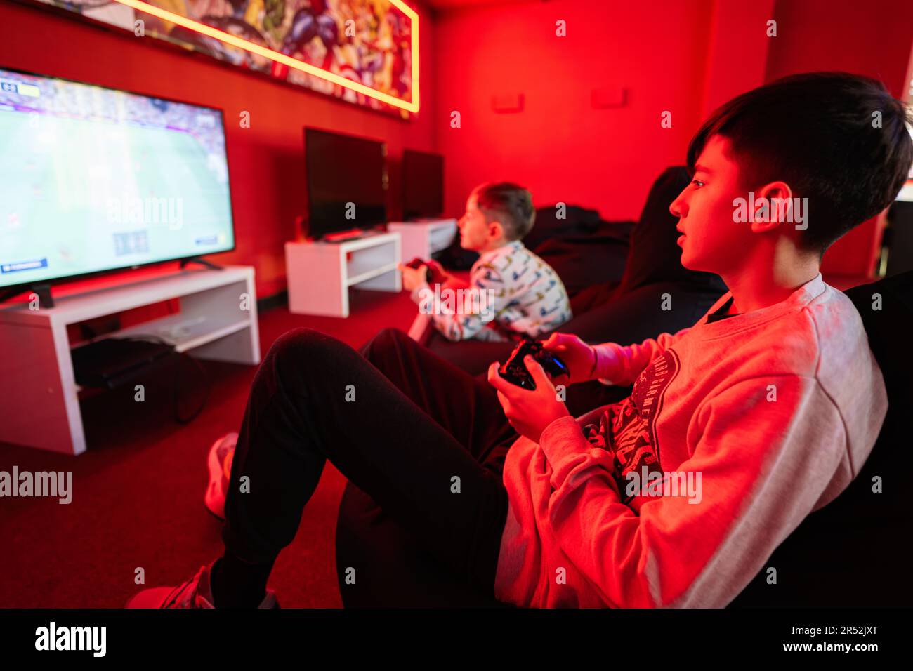 Two boys gamers play football gamepad video game console in red gaming ...