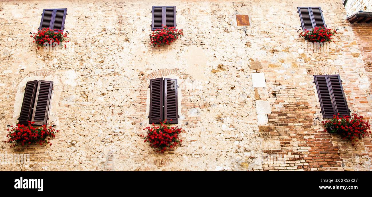 Tuscan windows with red flowers. Old wall in background Stock Photo - Alamy