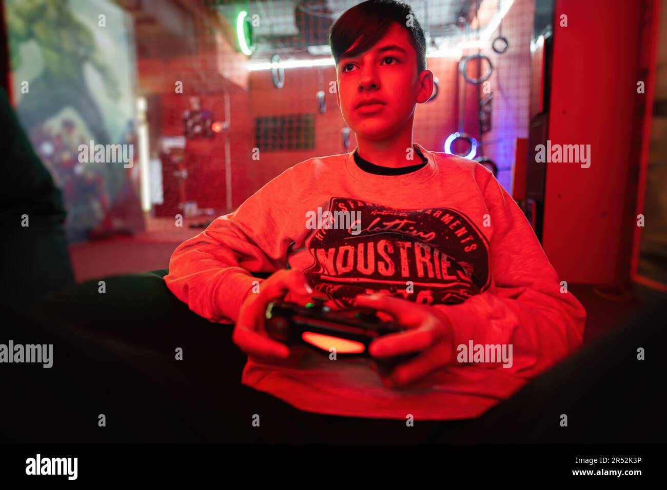 Teenager boy gamer play gamepad video game console in red gaming room ...