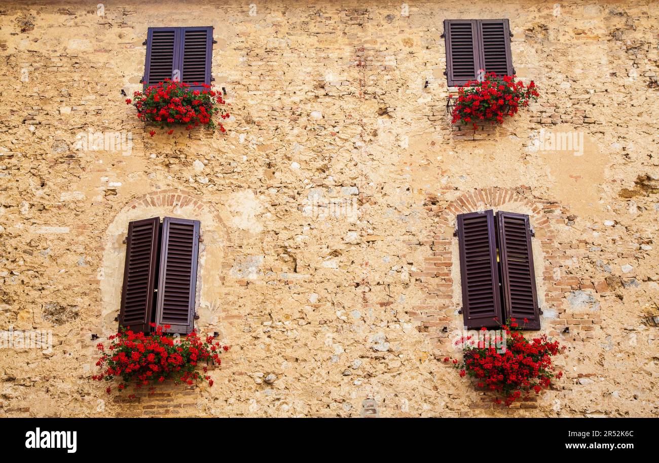 Tuscan windows with red flowers. Old wall in background Stock Photo - Alamy