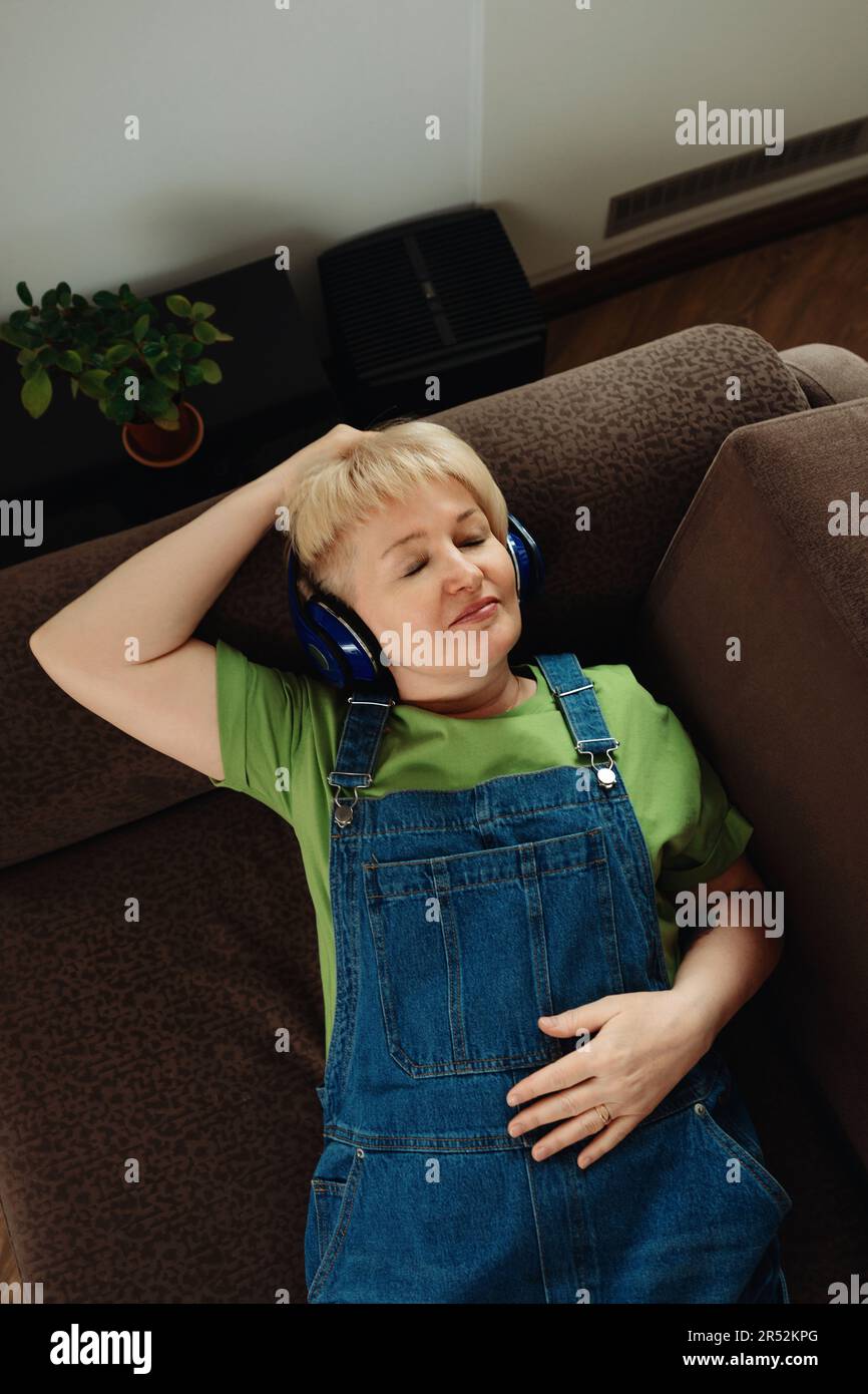 Non-binary woman relaxing at home enjoying tunes in headphones Stock Photo - Alamy