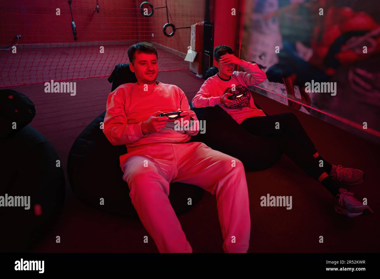 Father and son play gamepad video game console in red gaming room. Dad ...