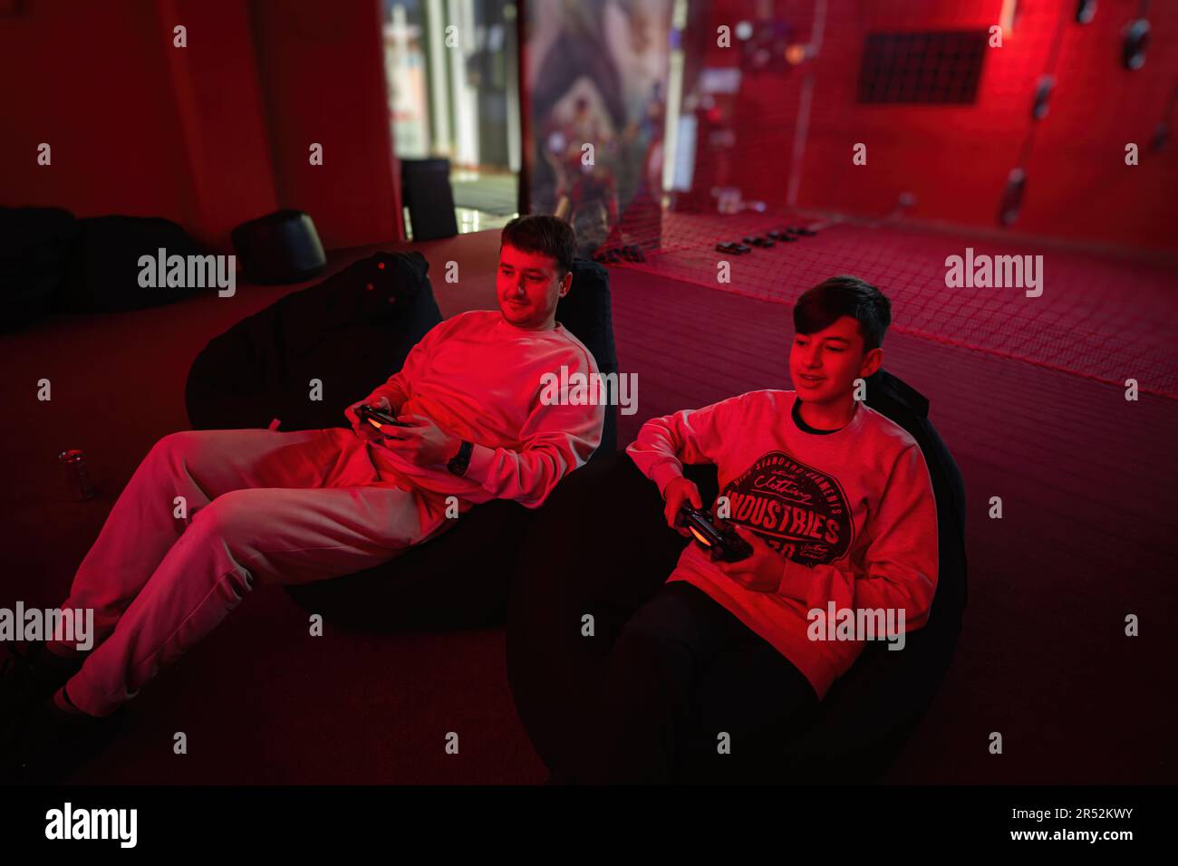 Father and son play gamepad video game console in red gaming room. Dad ...