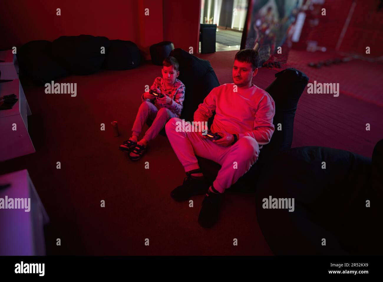 Father and son play gamepad video game console in red gaming room. Dad ...