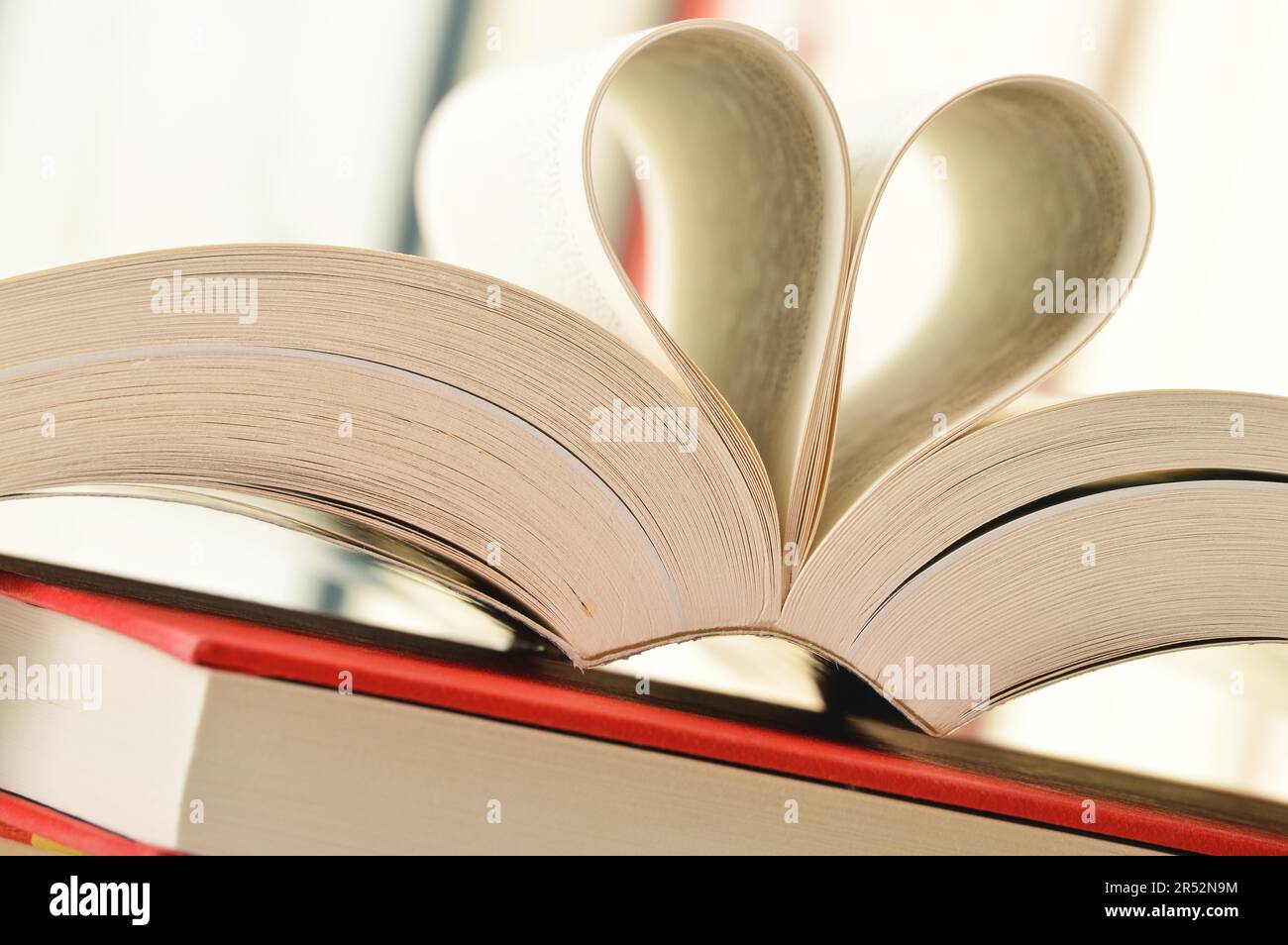 Composition with stack of books and pages formed in a shape of heart ...