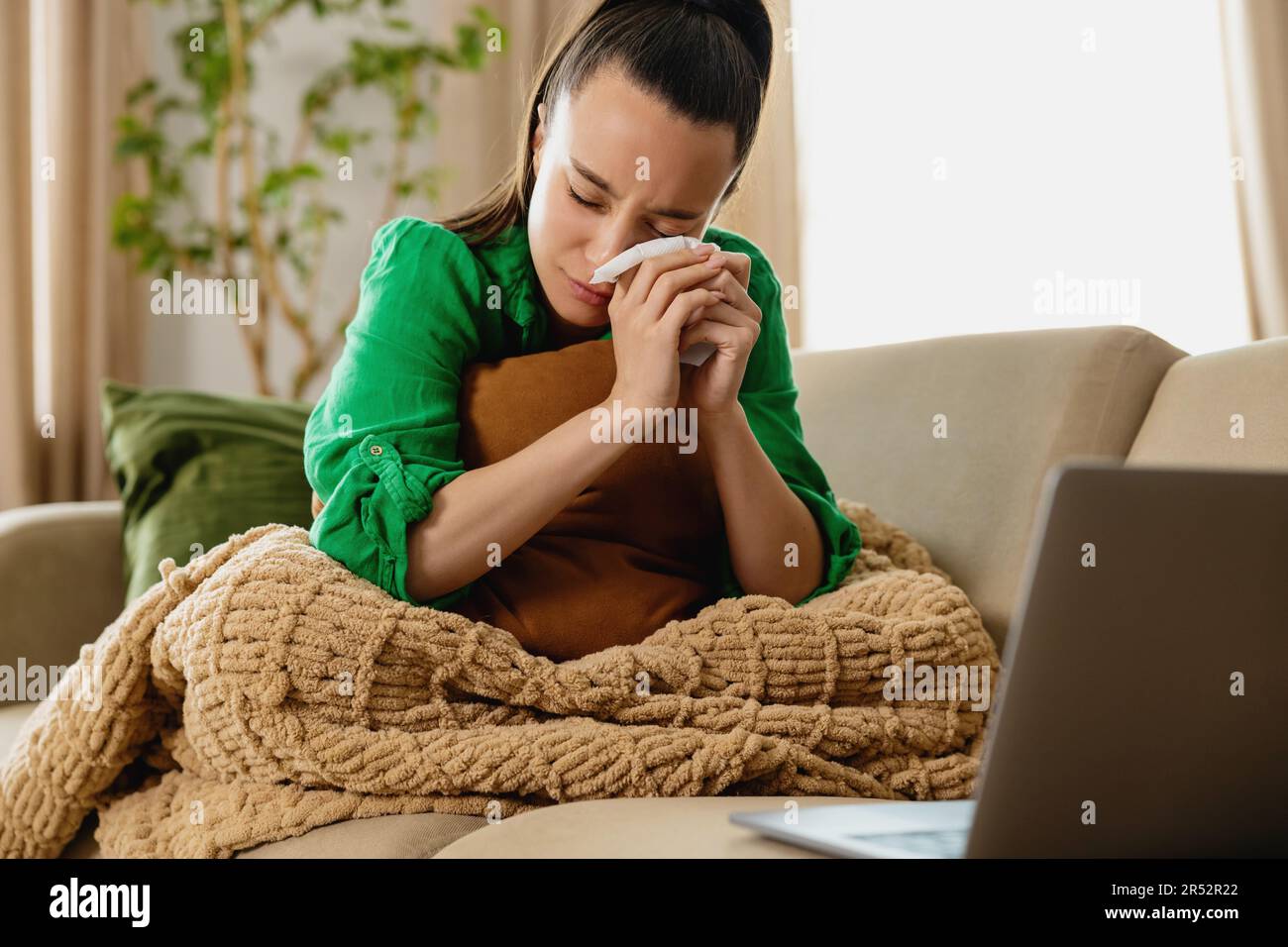 Young woman crying on couch in front of laptop Stock Photo - Alamy
