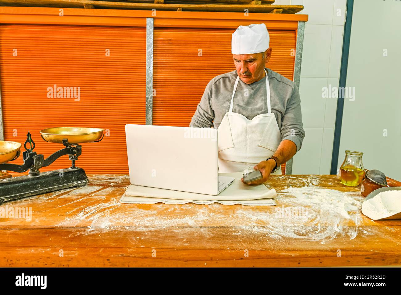 Baker consulting on the computer, at the work table Stock Photo - Alamy