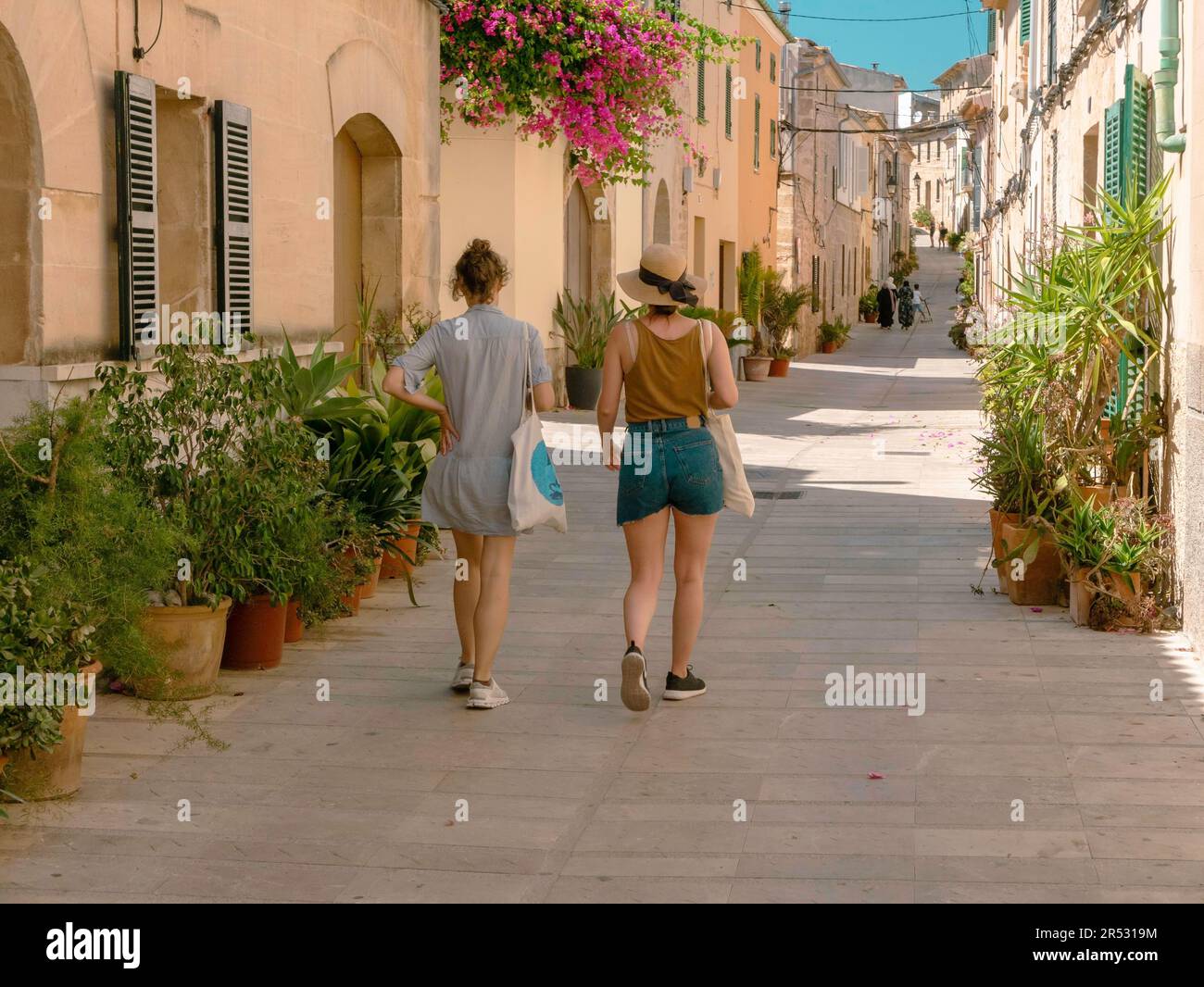 Two walking girls on the street in the old town of Alcudia, Mallorca ...
