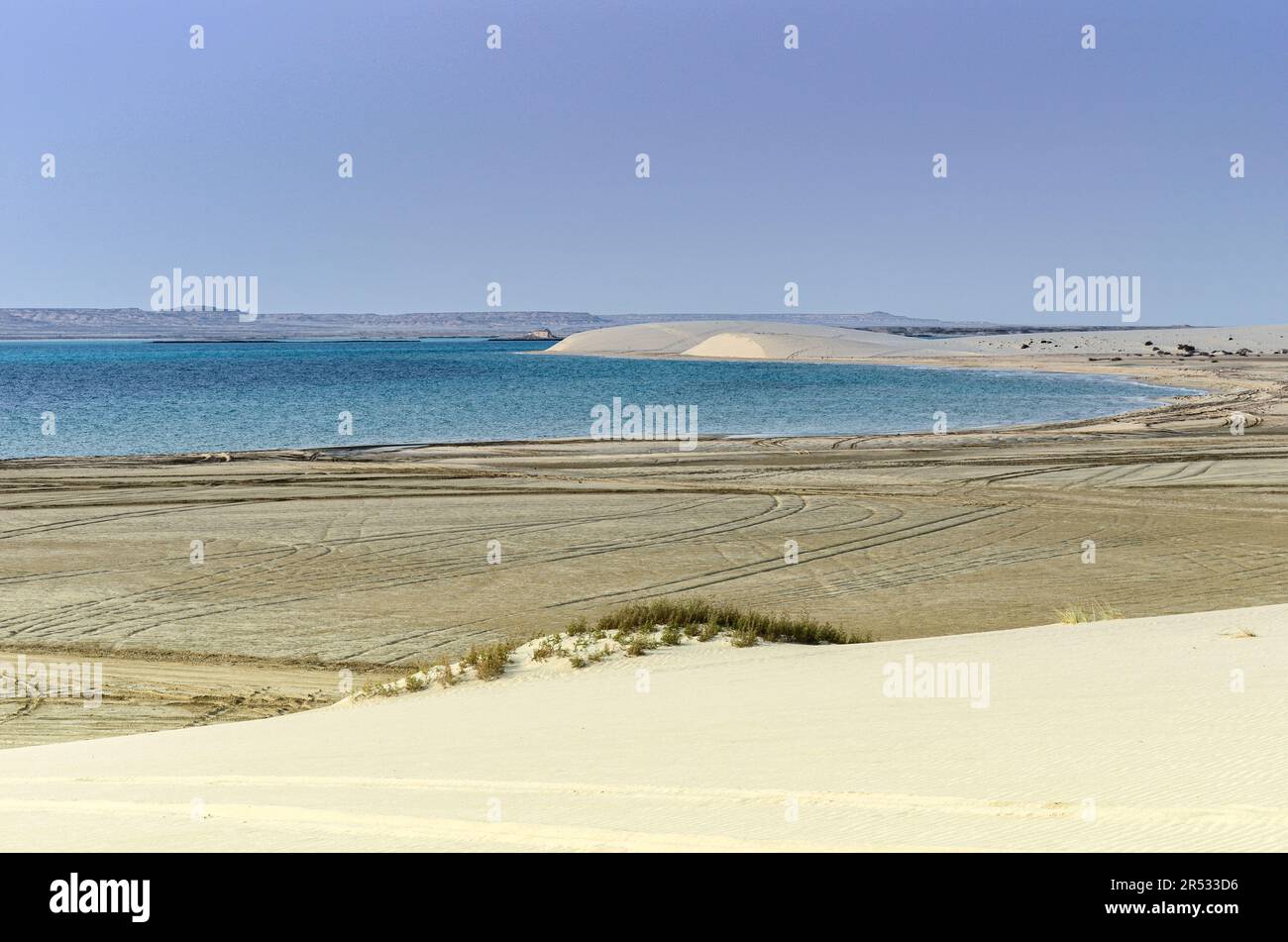 Sand dunes descending into the seal inlet with limestone hills in the ...