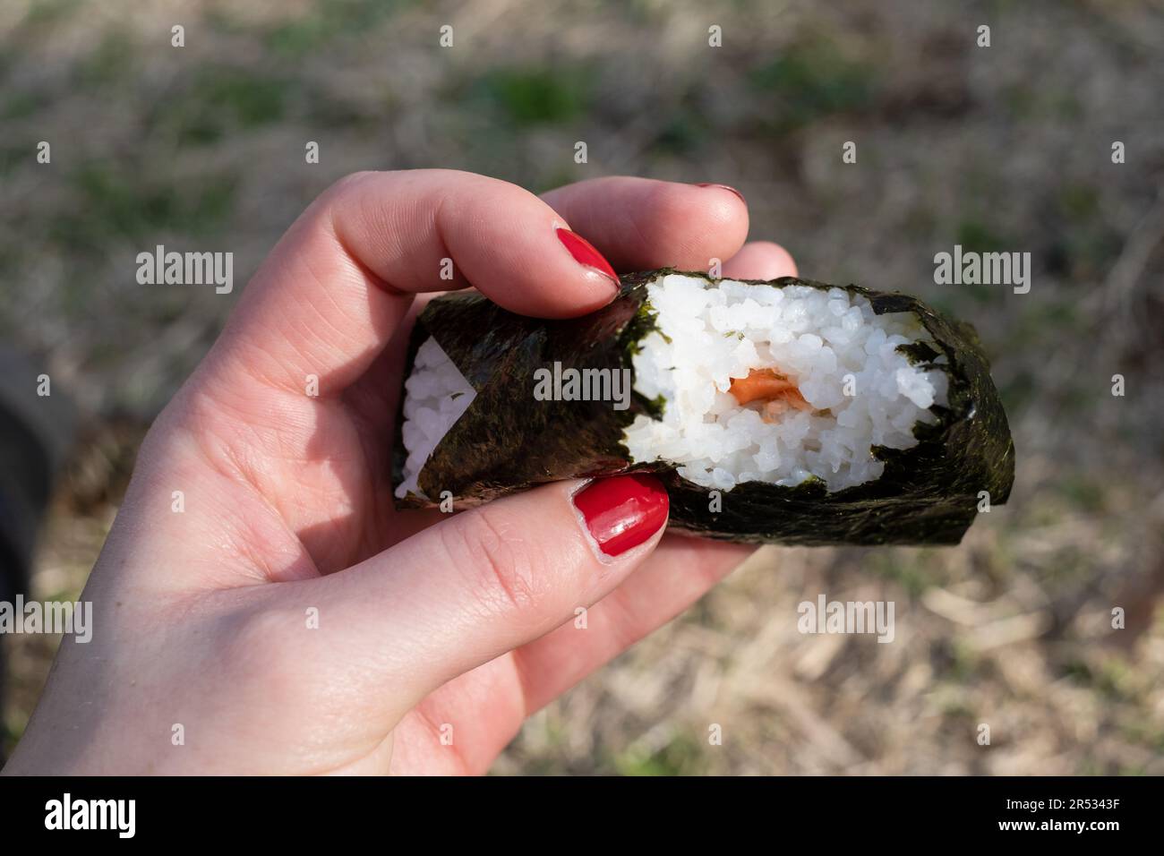Hand holding a Salmon Onigiri from a convenience store with a bite ...