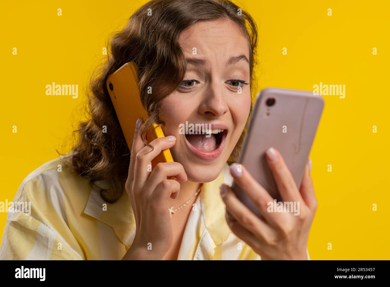 Irritated nervous stressed young woman talking screaming on two mobile ...