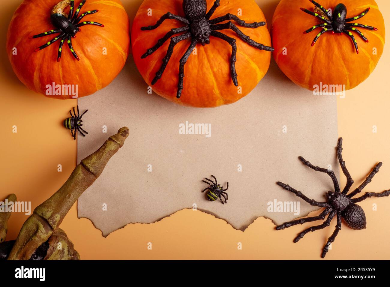 Sheet of paper with spiders, bats, pumpkin and monster hand on orange ...