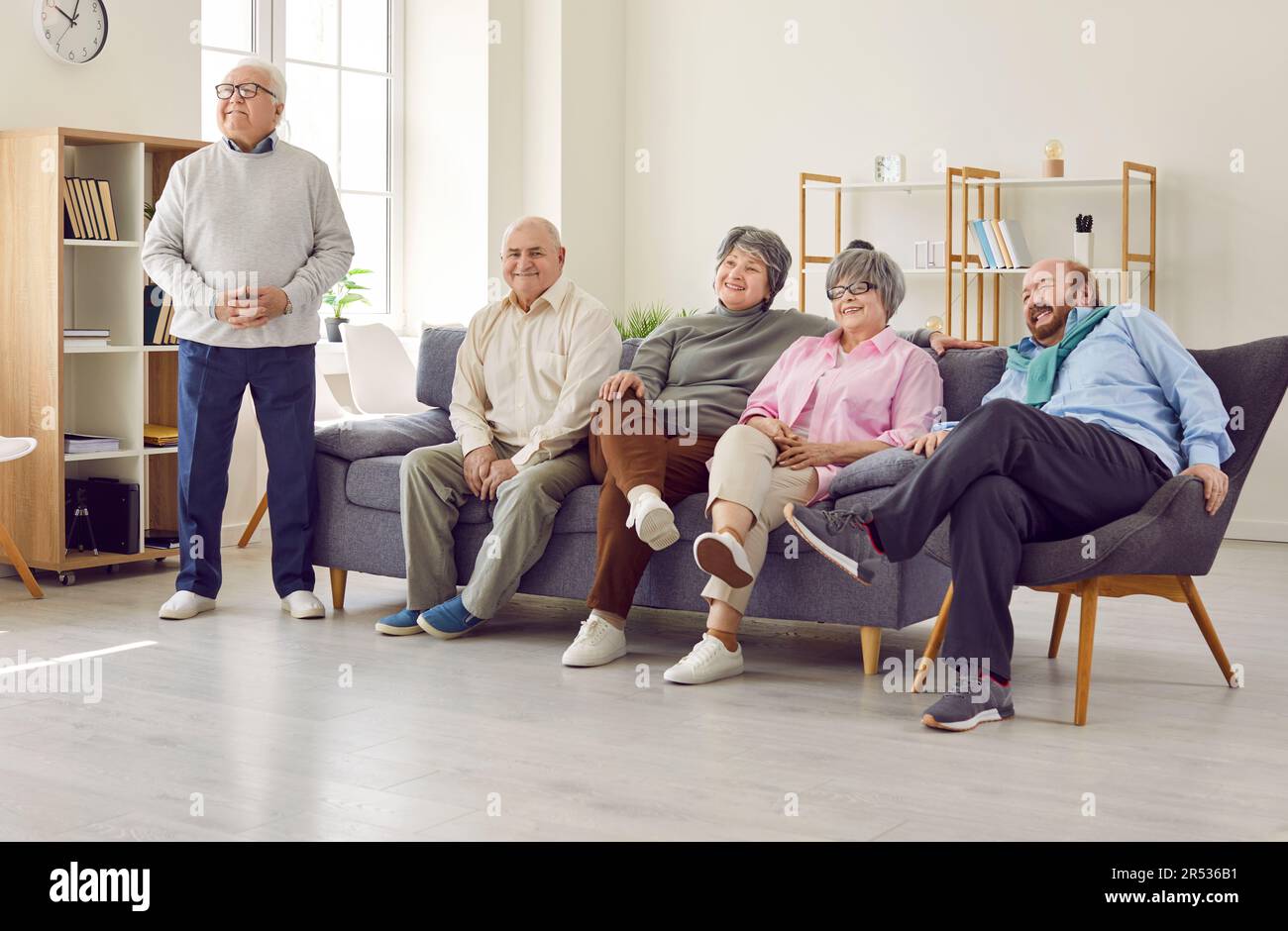 Group of happy senior people watching television at home or in ...