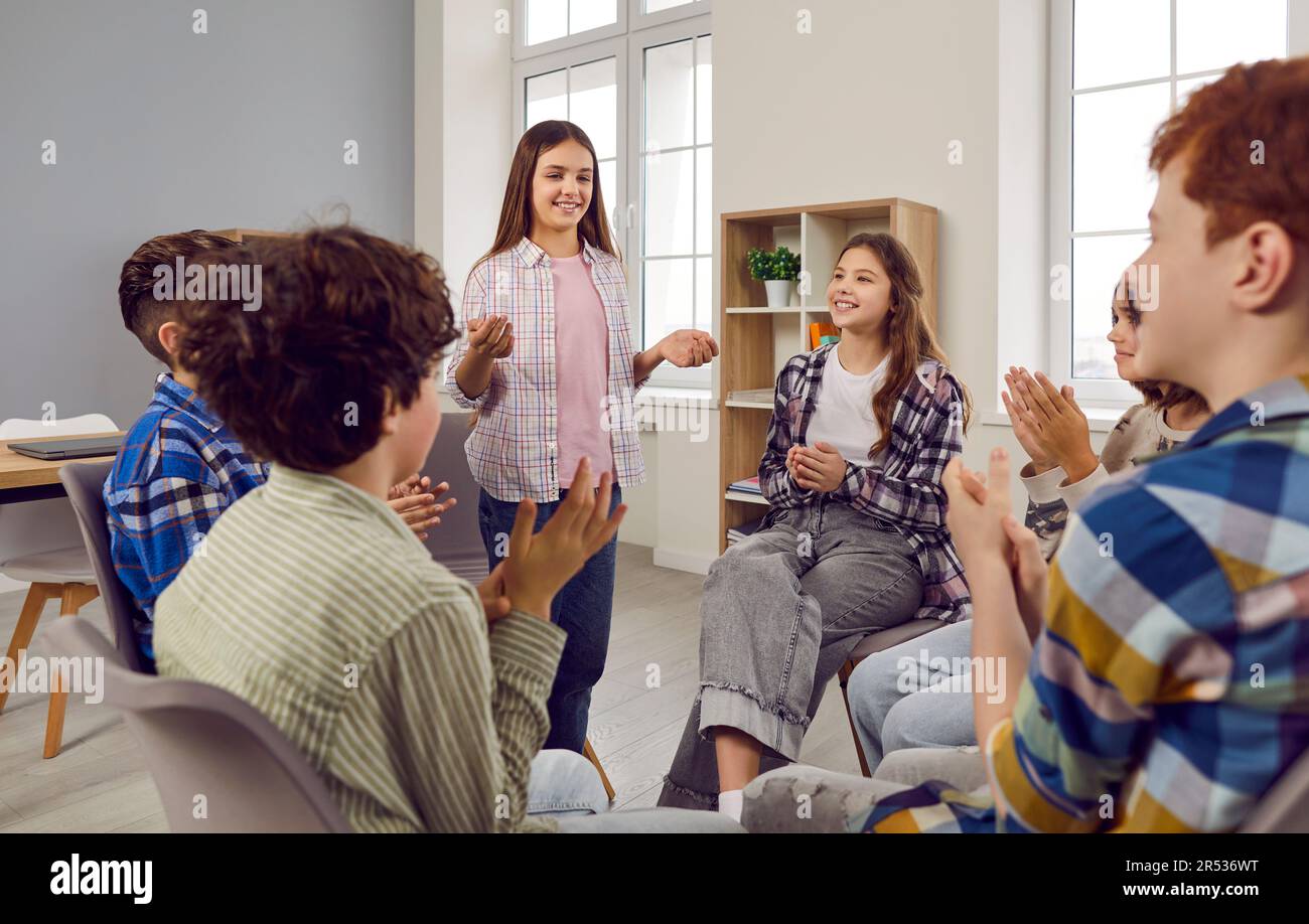 School children sitting in a circle in class and listening girl ...