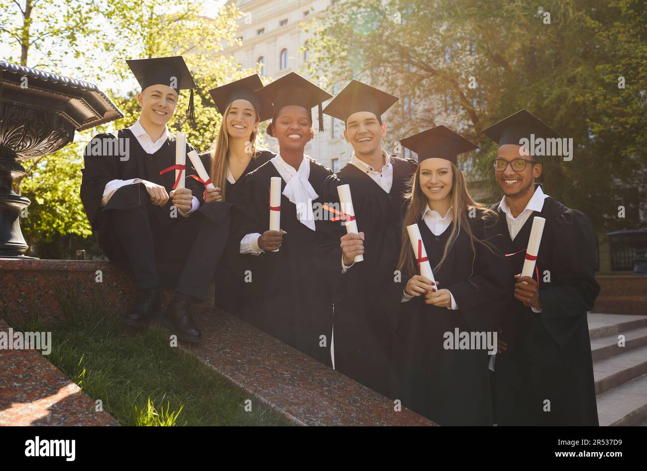 Happy college graduates standing in row with diplomas Stock Photo - Alamy
