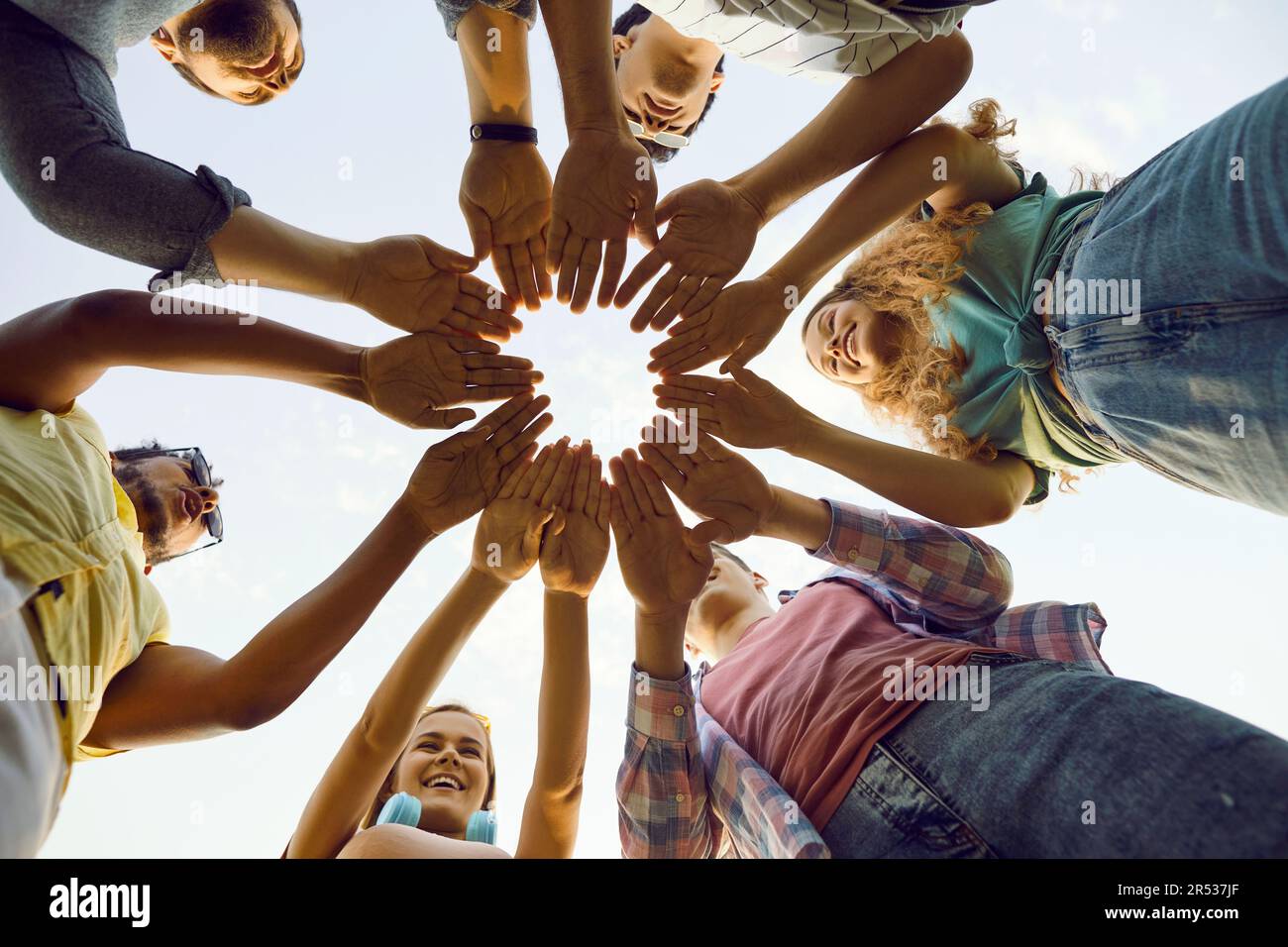 Group of friends stand outdoors making circle with their hands that ...