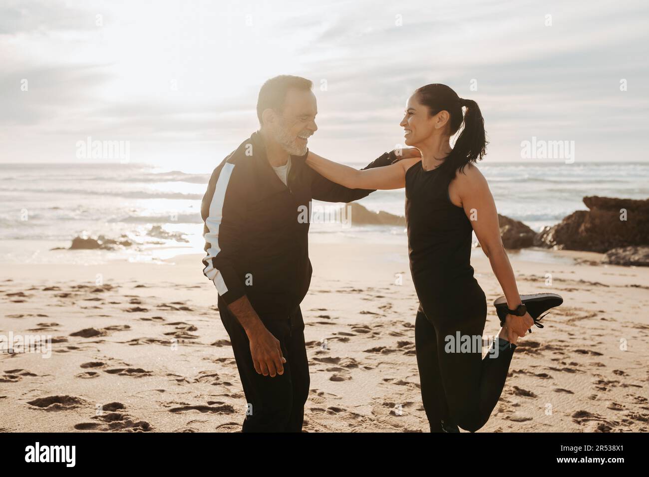 Positive mature european man and woman doing leg exercises, stretching ...