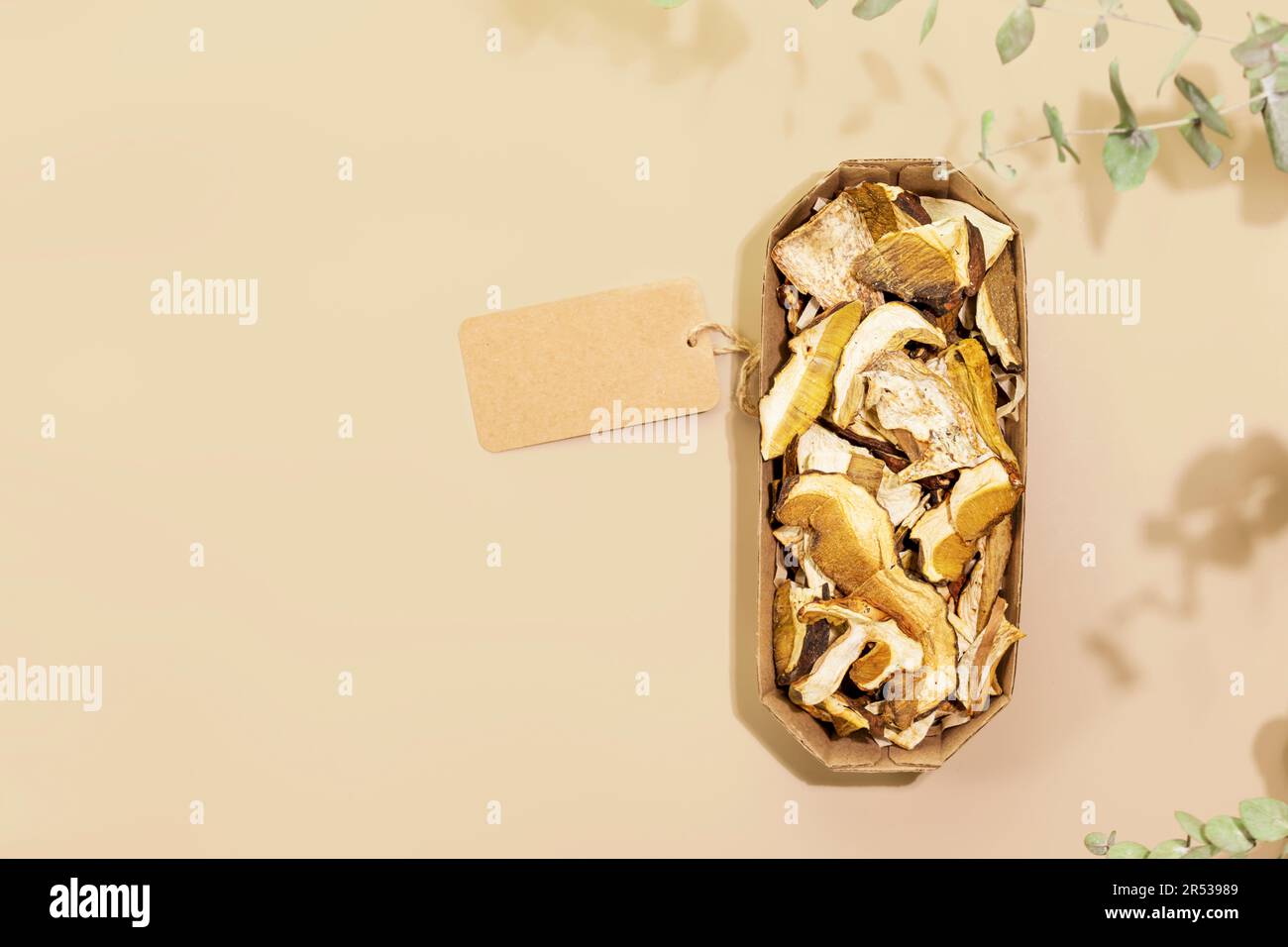Dry porcini mushrooms in cardboard box with empty label on beige ...