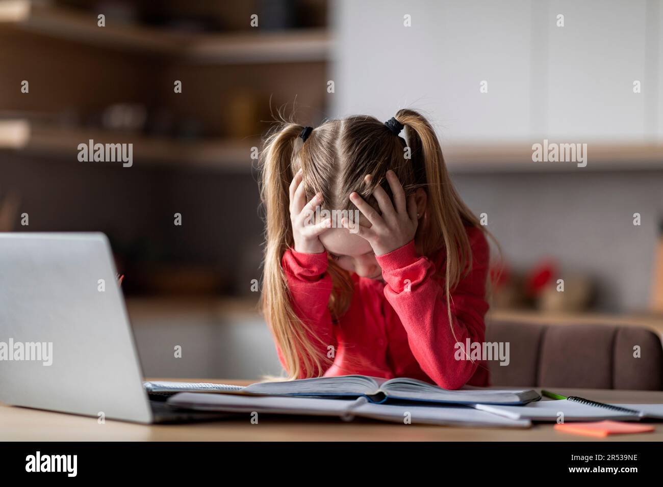 Little schoolgirl suffering while doing homework, tired of reading book ...