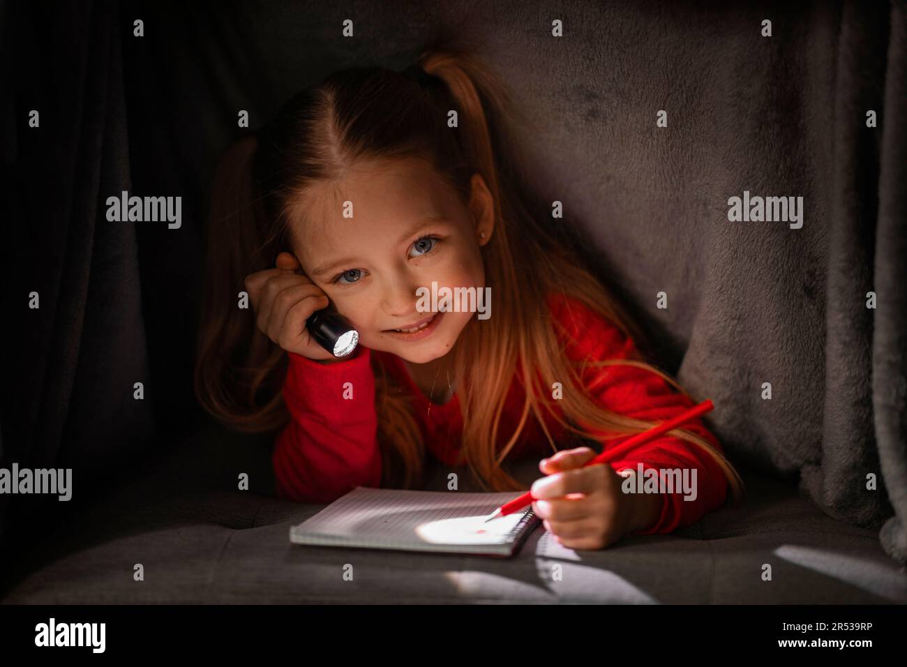 Cute Smiling Girl Hiding Under Blanket With Flashlight And Writing In ...