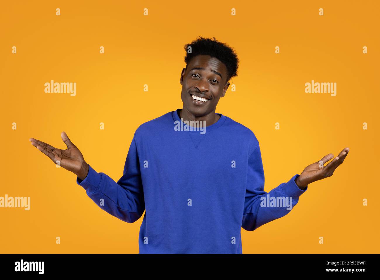 Handsome young black man spread hands sideways, yellow background Stock ...