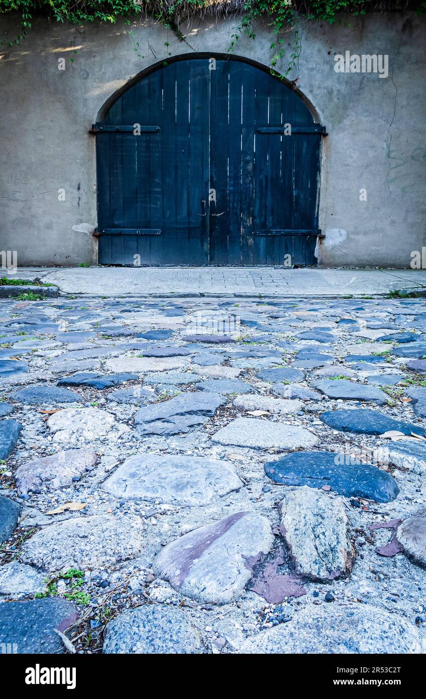 A very low angle photo on a cobblestone street facing a double door ...