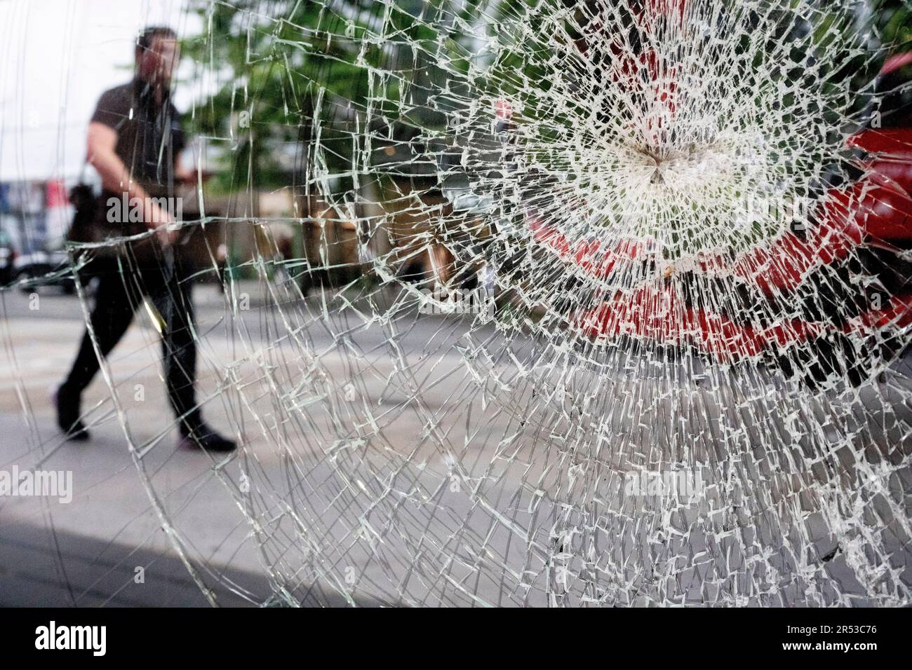 Members of the public walk through the city, passing a smashed window ...