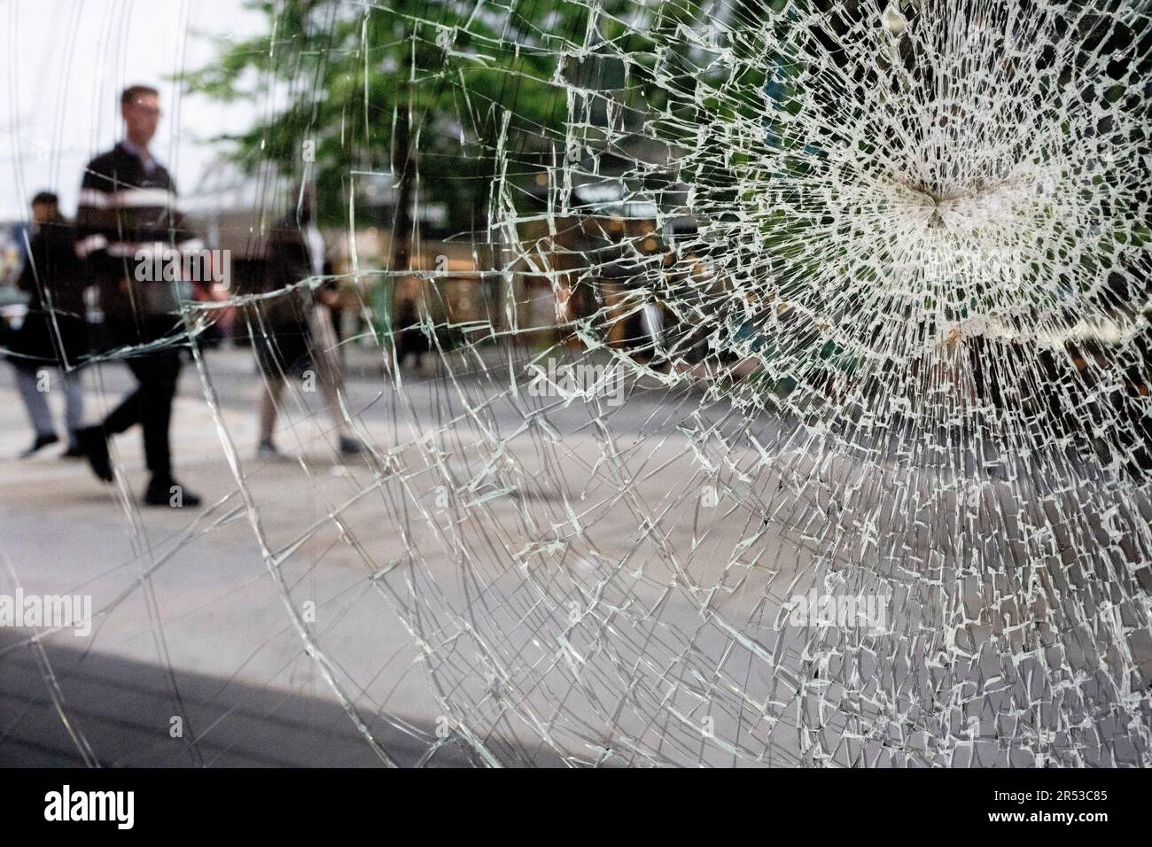 Members of the public walk through the city, passing a smashed window ...