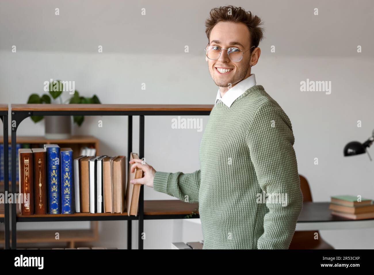 Young man taking book from shelf in library Stock Photo - Alamy