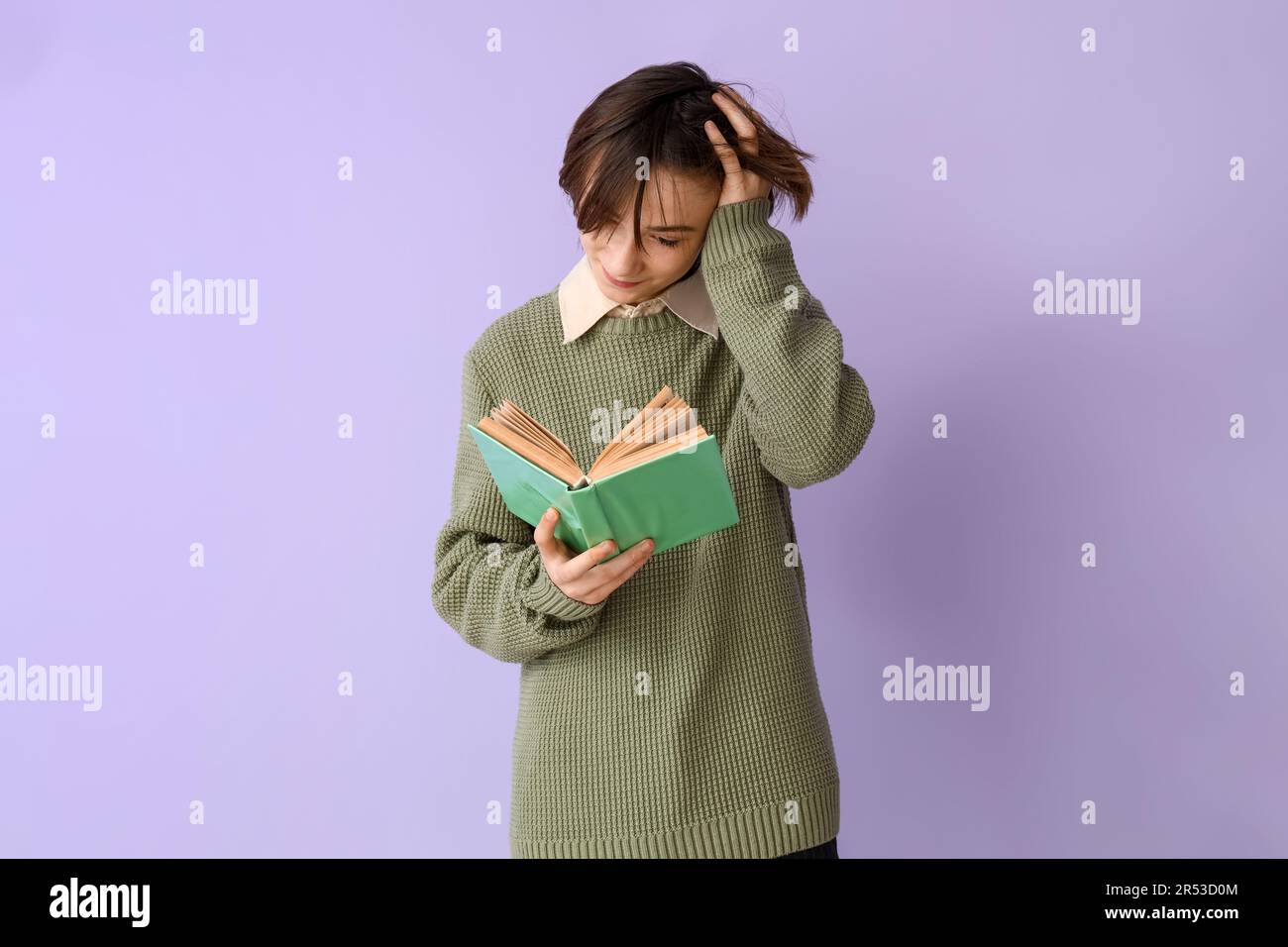 Teenage boy reading book on lilac background Stock Photo - Alamy