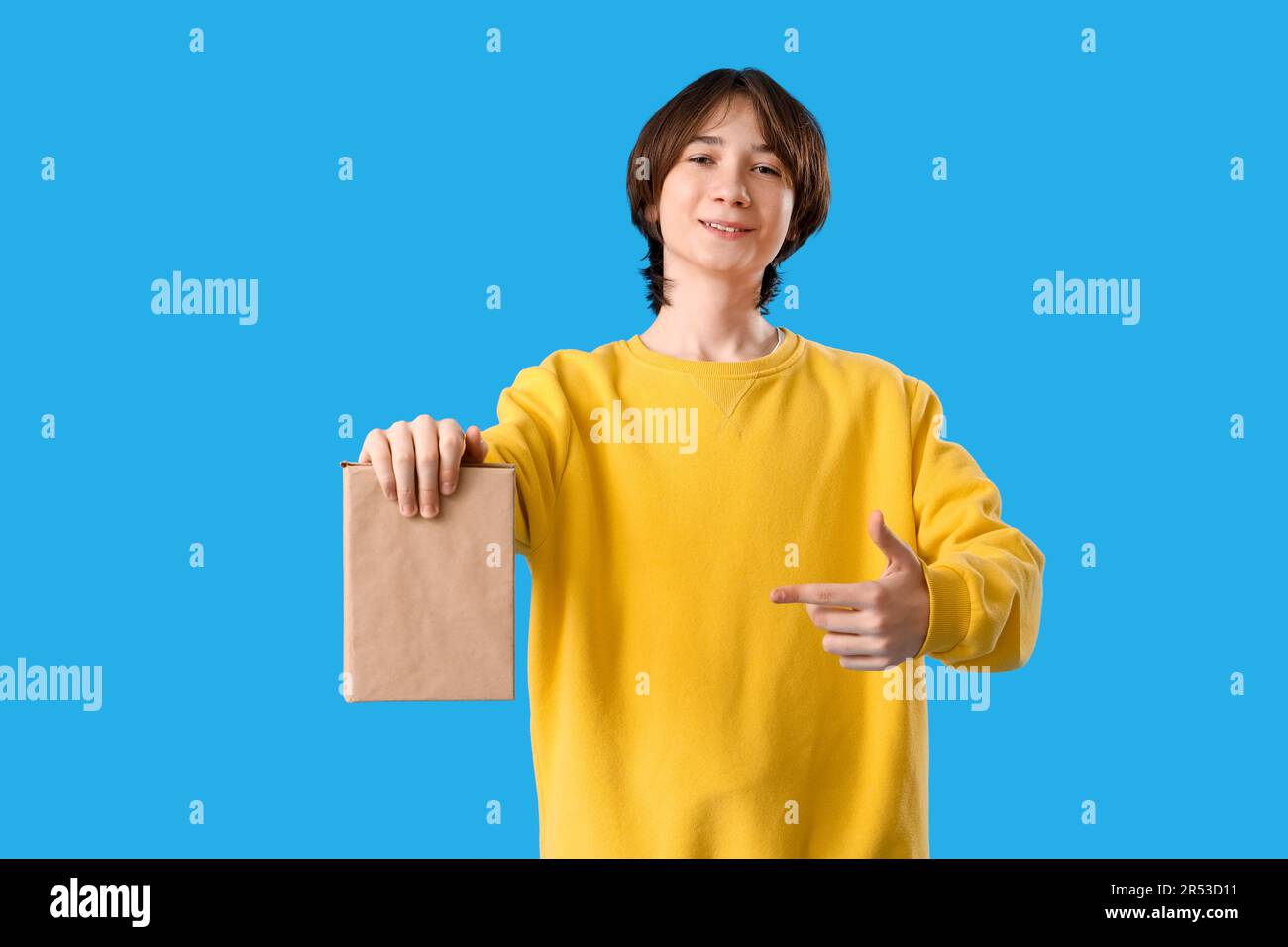 Teenage boy pointing at book on blue background Stock Photo - Alamy