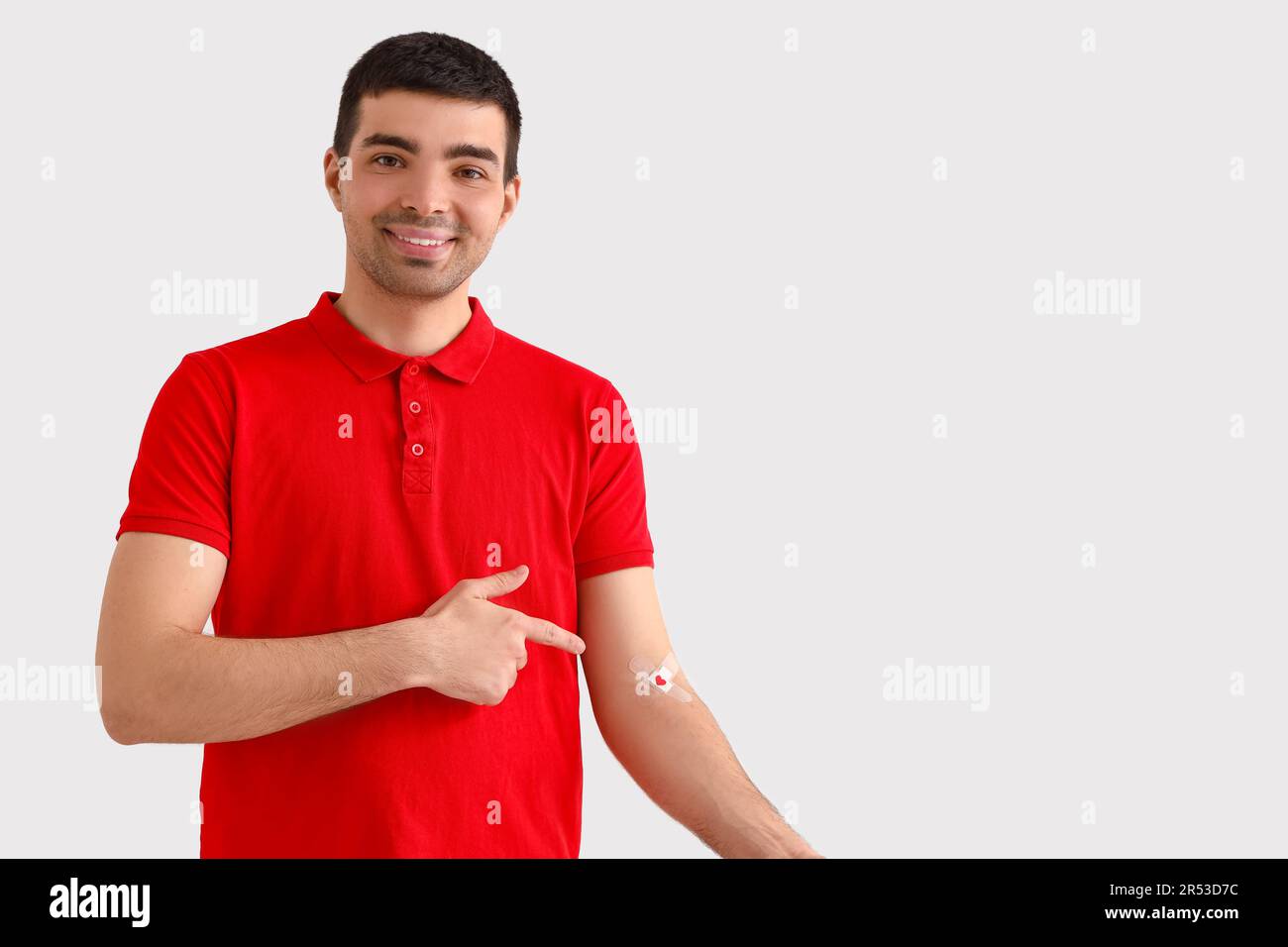 Young blood donor pointing at applied medical patches on light ...