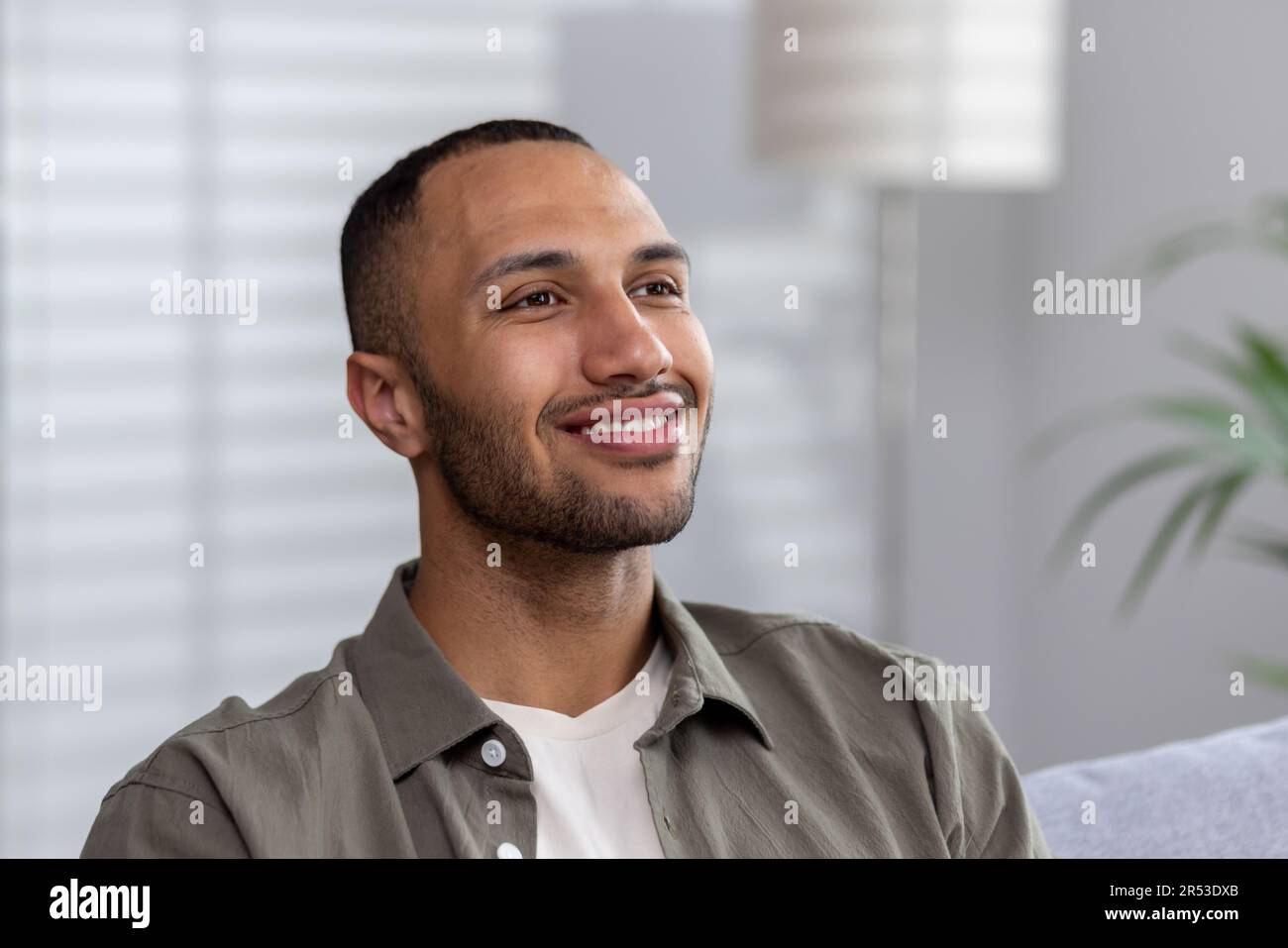 Portrait of a young Latin American man relaxing on the couch at home ...