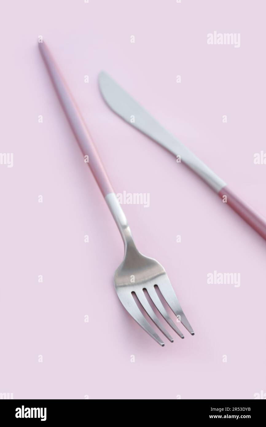 Stainless steel fork and knife on pink background Stock Photo - Alamy