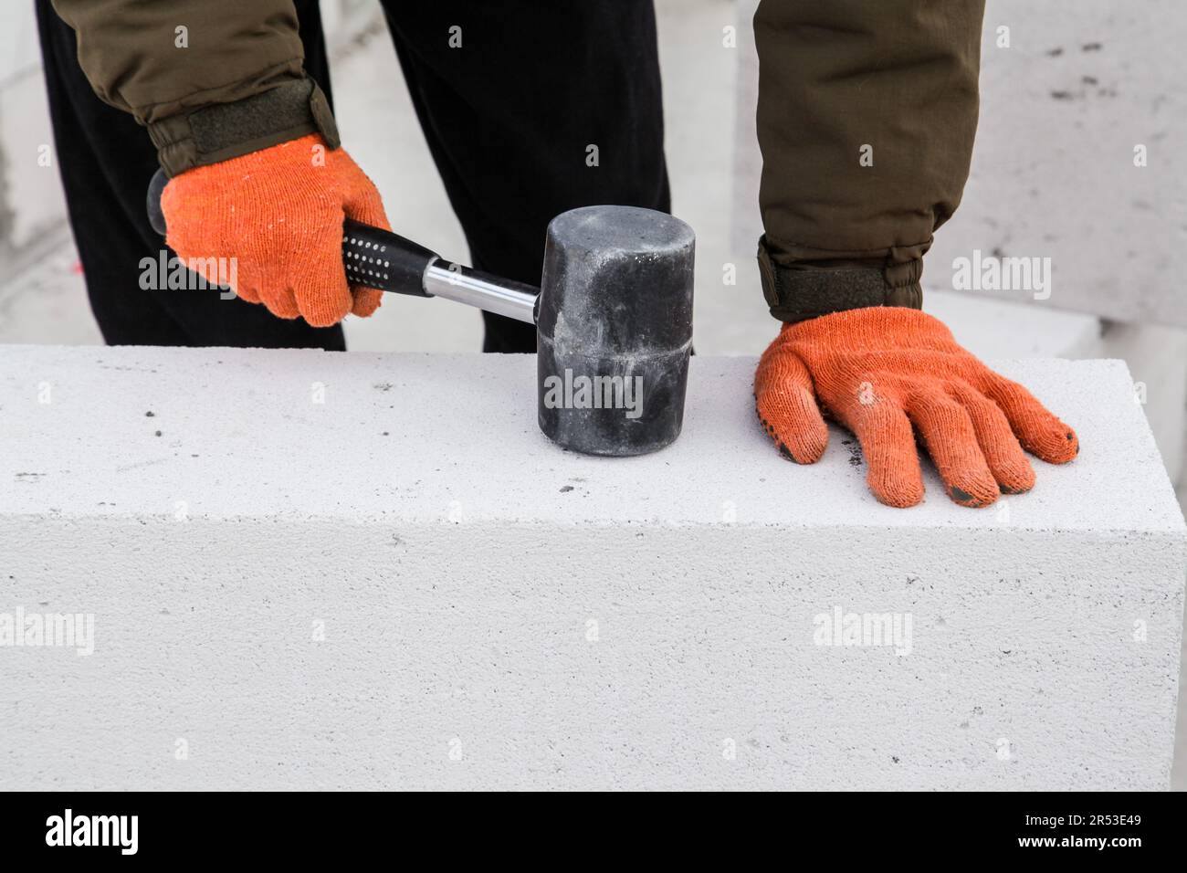 Construction worker beating aerated concrete block with Rubber Hammer ...