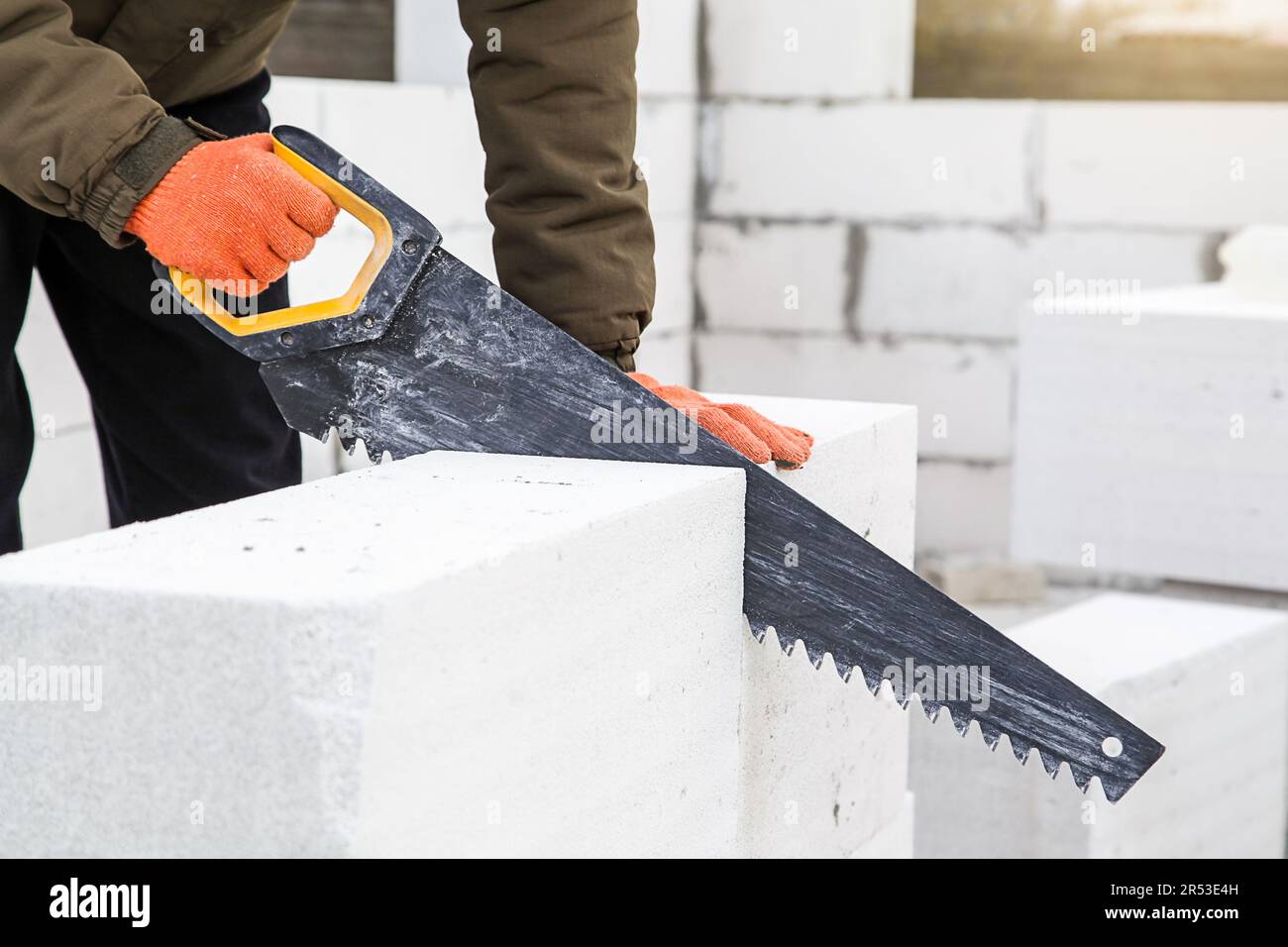 Builder sawing aerated concrete block with hand saw at construction ...