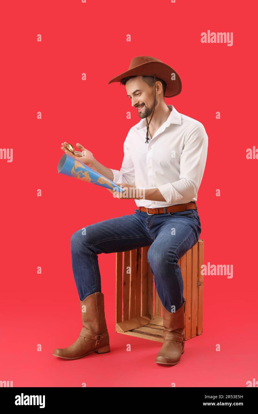 Handsome cowboy with compass and world map sitting on red background ...