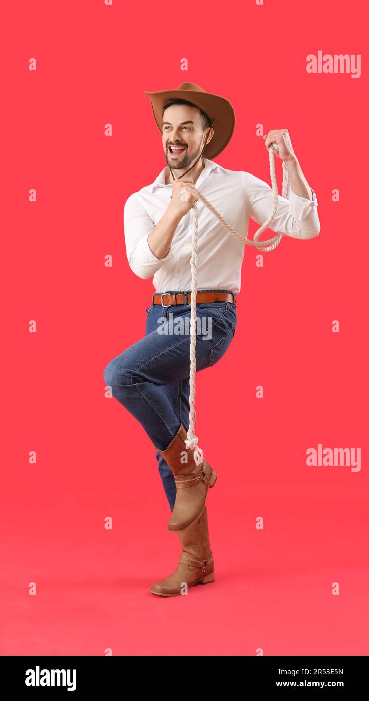Handsome cowboy with lasso on red background Stock Photo - Alamy
