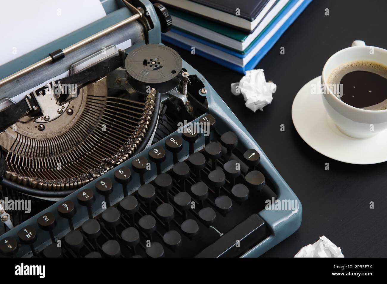 Vintage typewriter with cup of coffee and books on black background ...