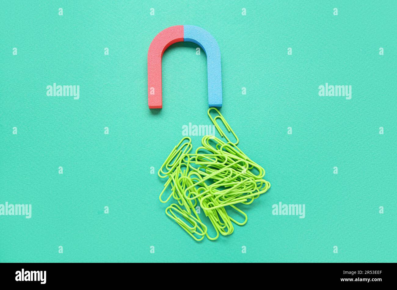 Magnet with heap of paper clips on green background Stock Photo - Alamy