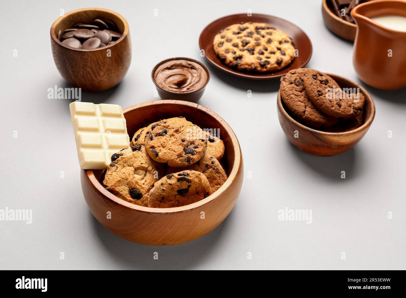 Bowls with cookies, chocolate and jug of milk on white background Stock ...