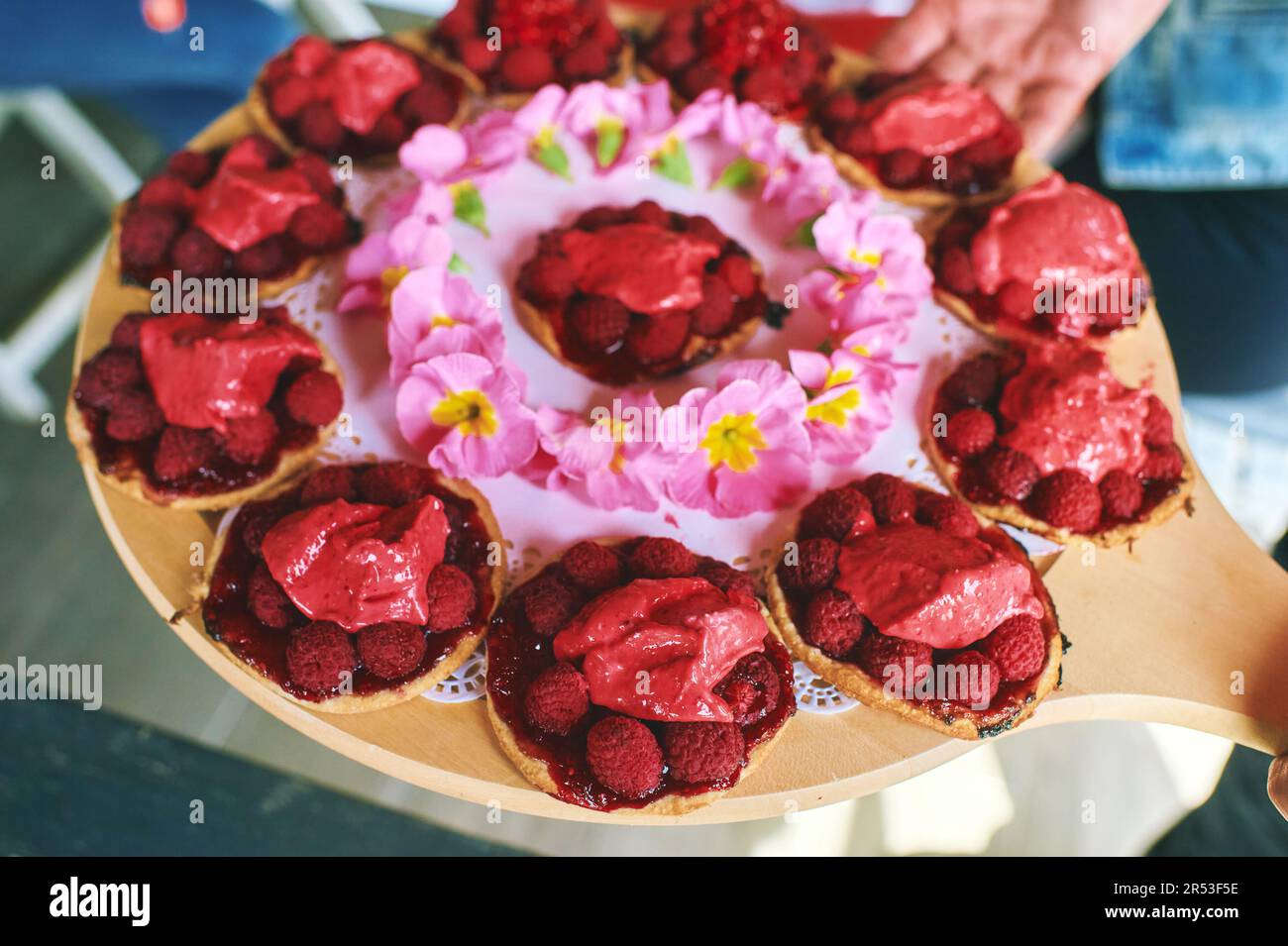 Person holding tray with many fresh fruit pie tart with with ...