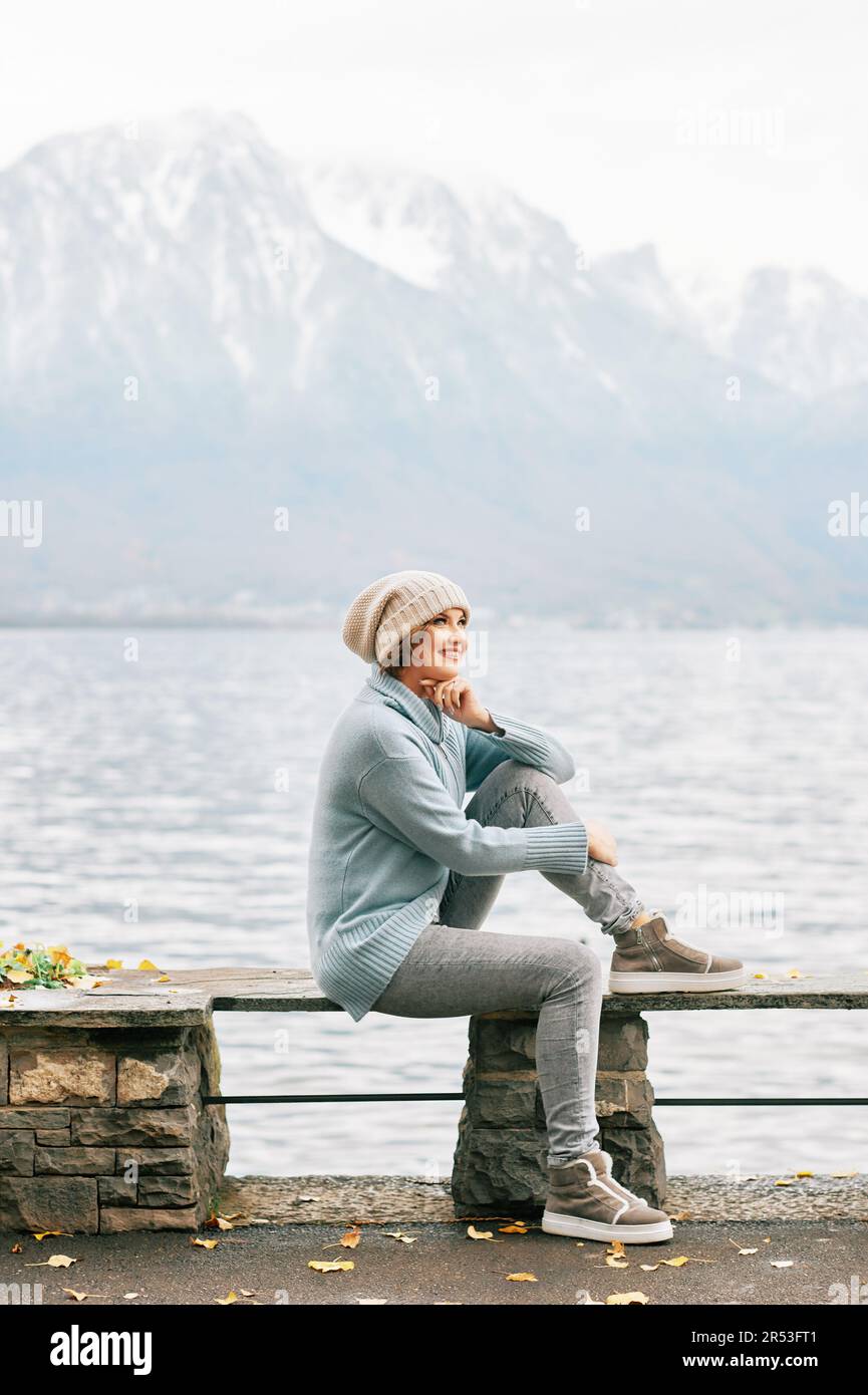 Outdoor portrait of beautiful young woman relaxing by mountain lake ...