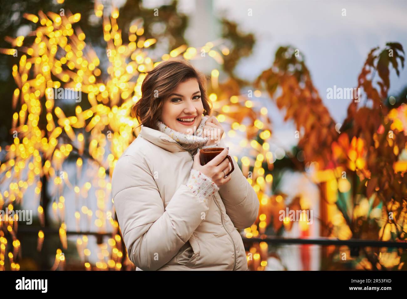 Winter portrait of happy young woman drinking hot chocolate outside at ...