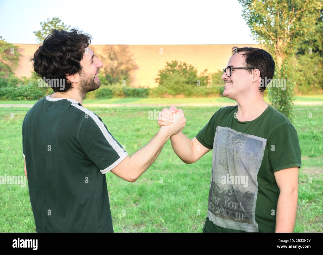 Two friends high-fives happily after working out in park with grass on ...