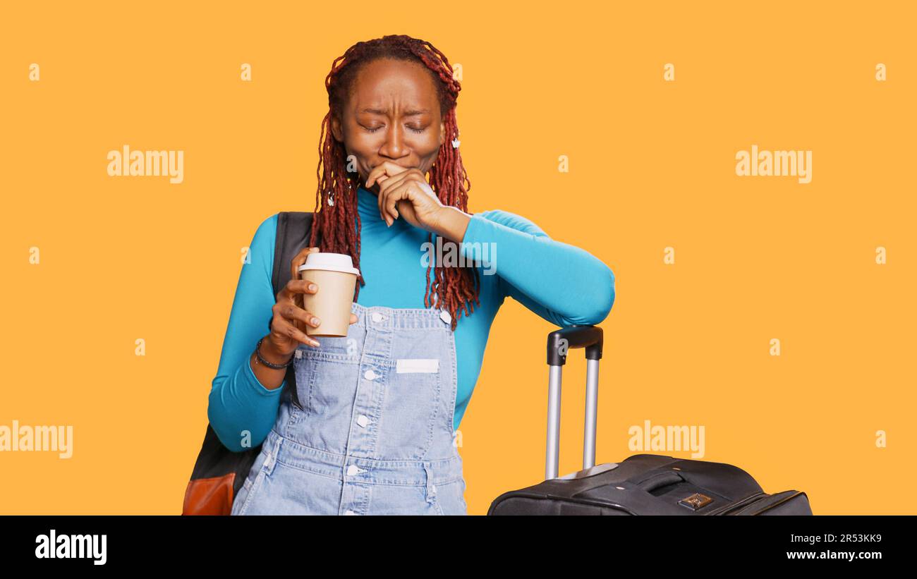 Exhausted woman drinking coffee cup and yawning in studio, preparing to ...
